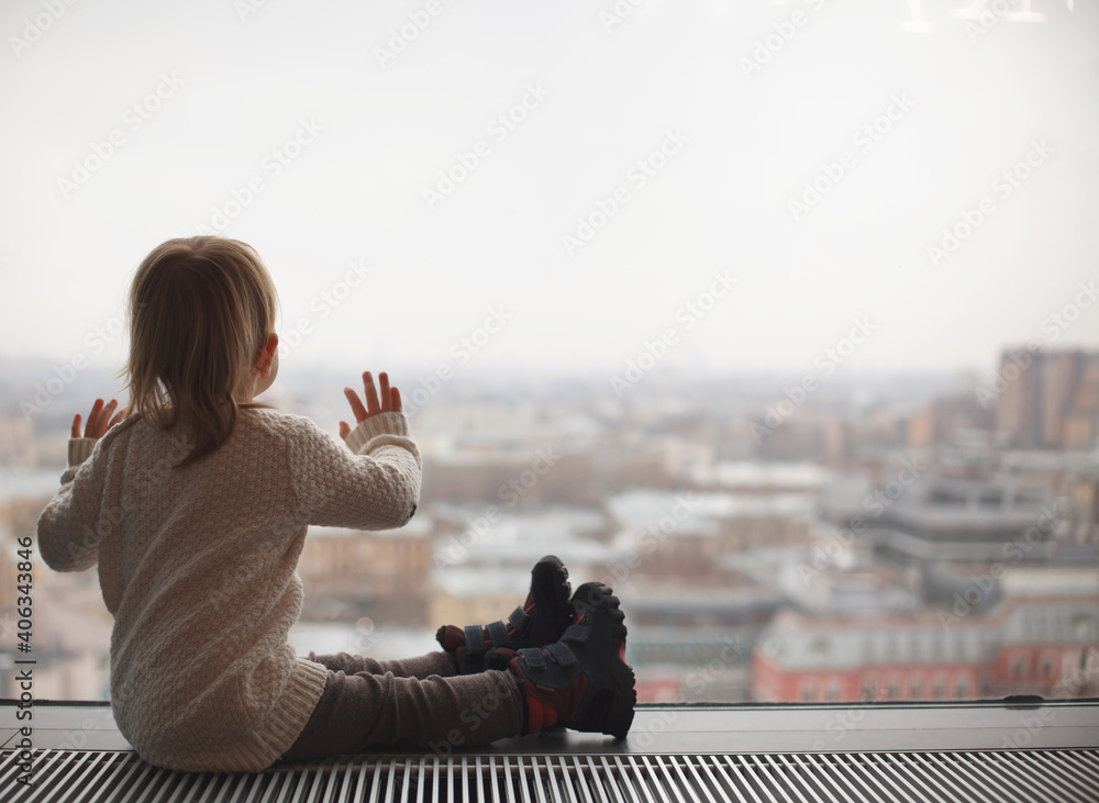 Baby girl sitting at the window. Looking through the window. In a ...