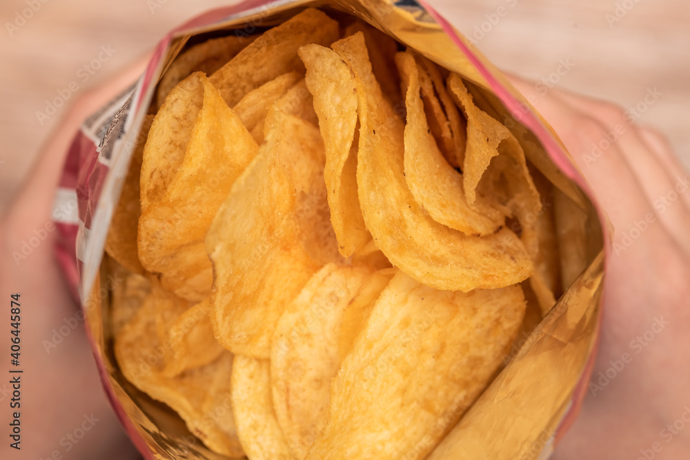 Hands hold a bag of potato chips. Junk food made from cholesterol ...