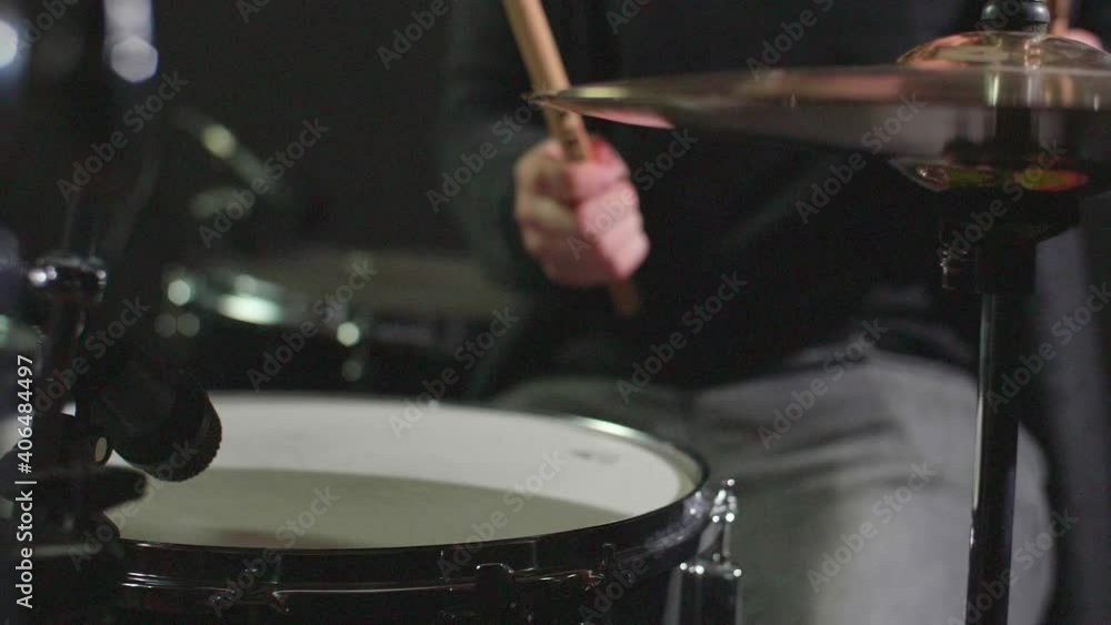 Smooth slow motion of a drum set being played in front of a dark ...