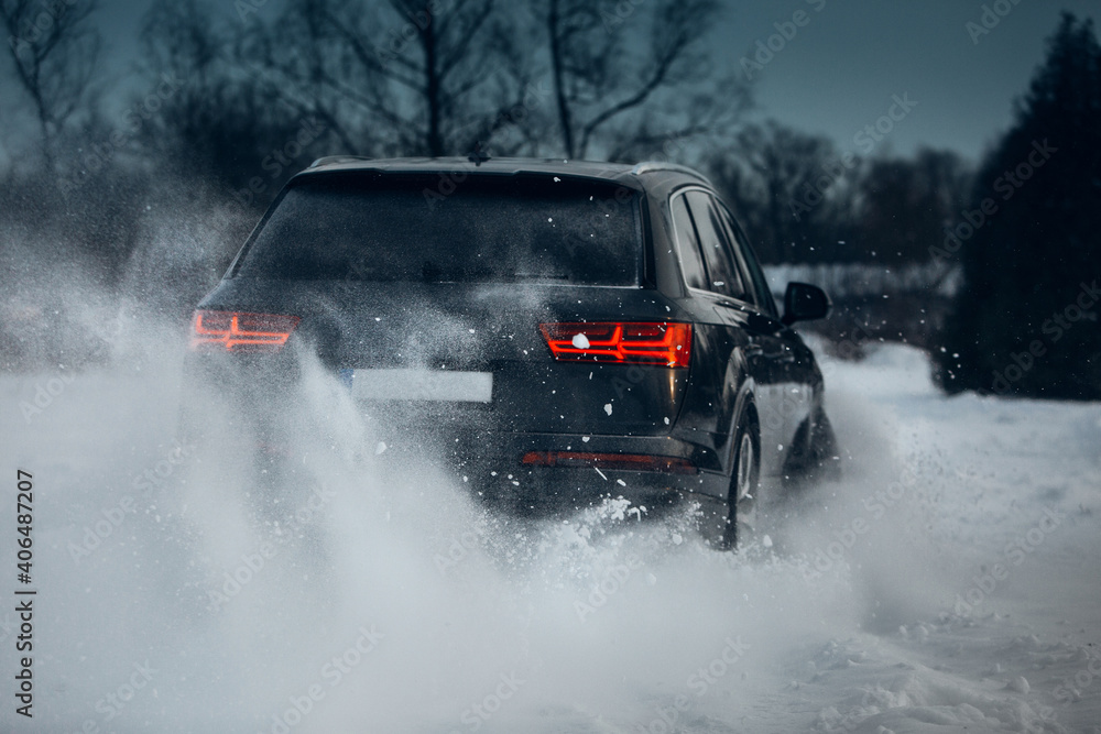 Modern and luxury SUV car go fast at the snow road, with splashes and ...