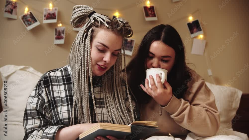 Two girlfriends laying in bed and reading book together Stock Video ...