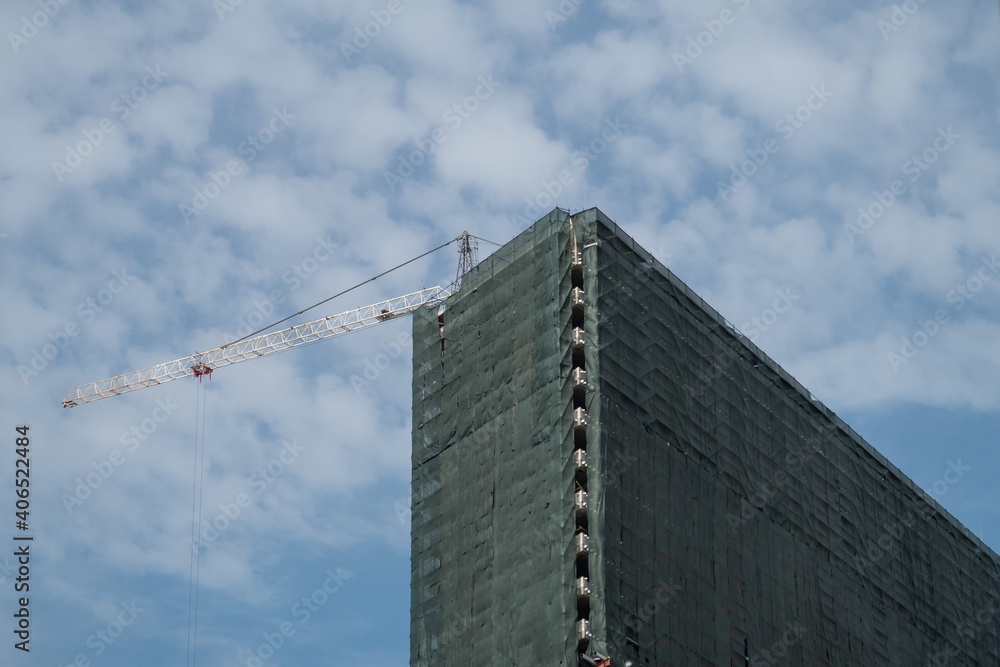 Tall building under construction completely covered with green ...