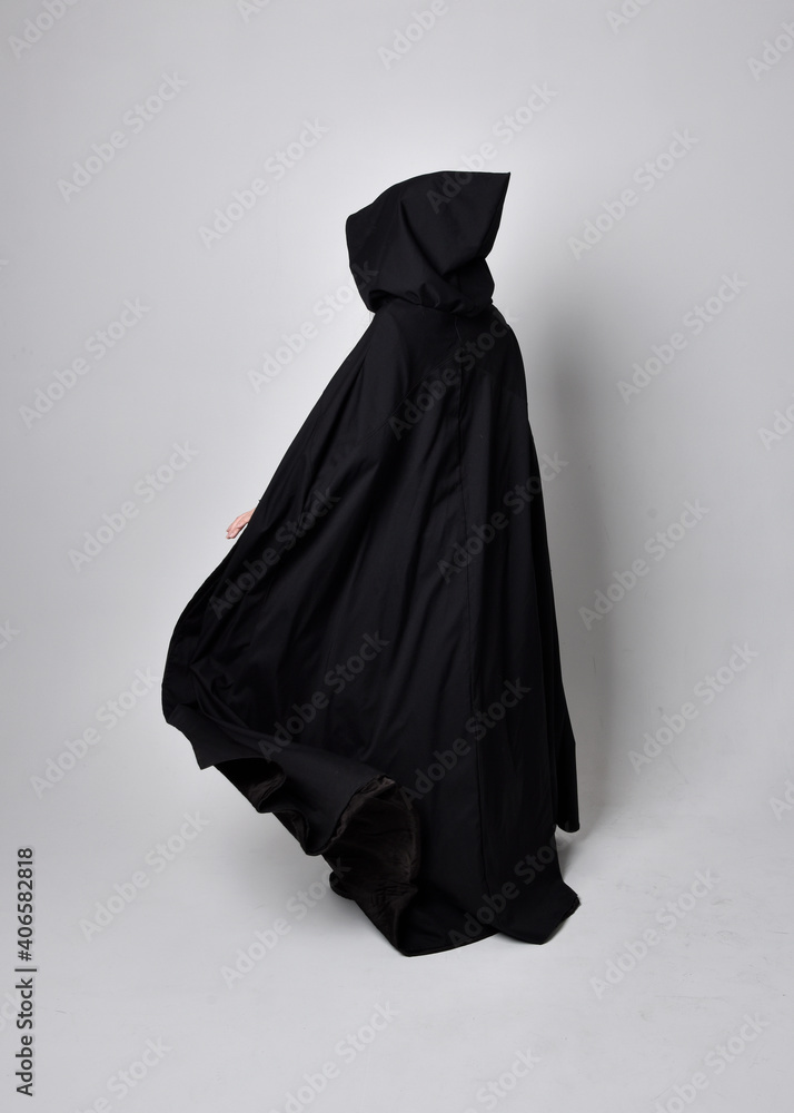 Full length portrait of pretty black haired woman wearing long dark gown nada cloak. Standing ...