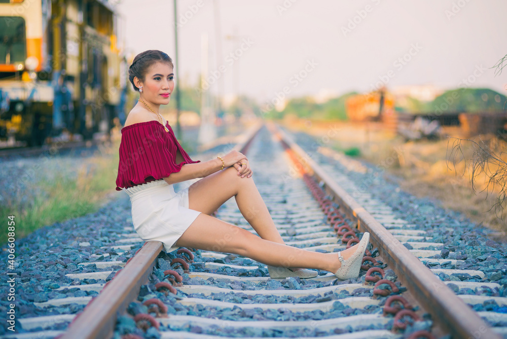 Attractive teen girl sitting on railroad tracks. Stock Photo | Adobe Stock