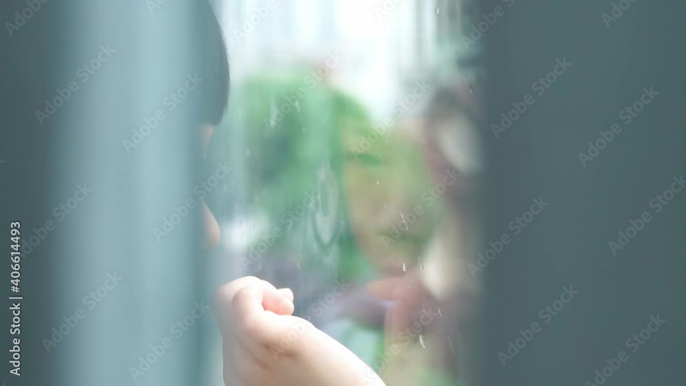 An Autistic child draw stick figure with finger on fogged glass window ...