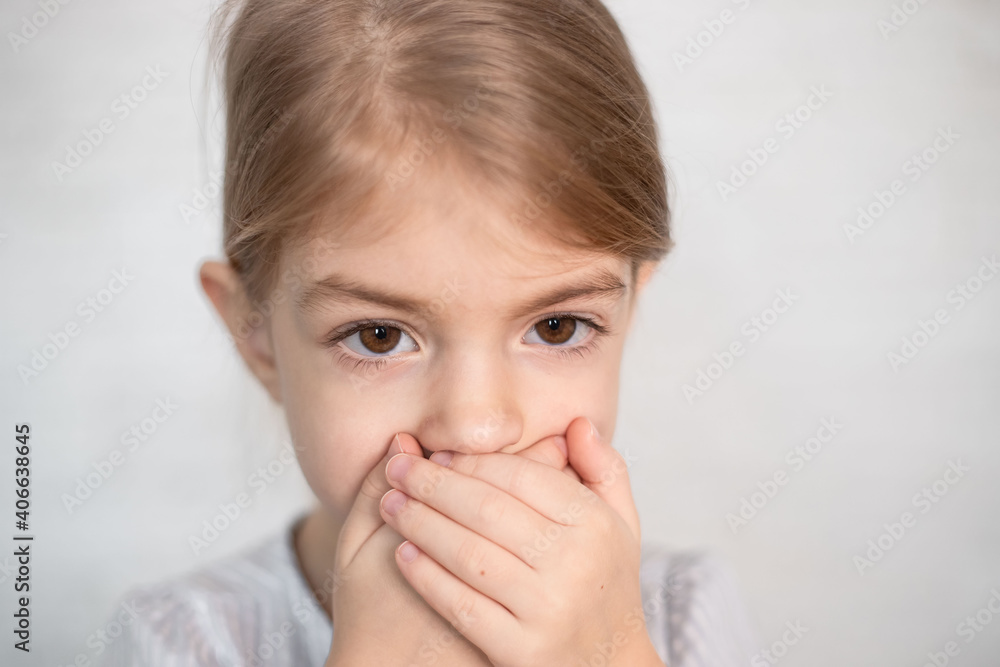 portrait of little girl, child closing his mouth with hands. Speech ...