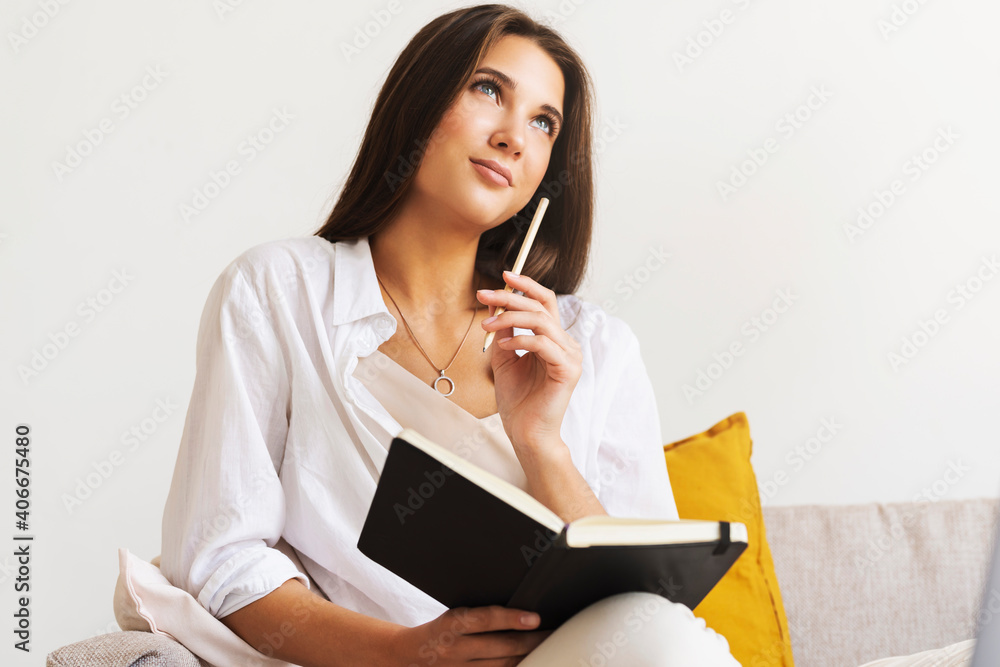 Beautiful brunette woman in white shirt sits on sofa in home office ...