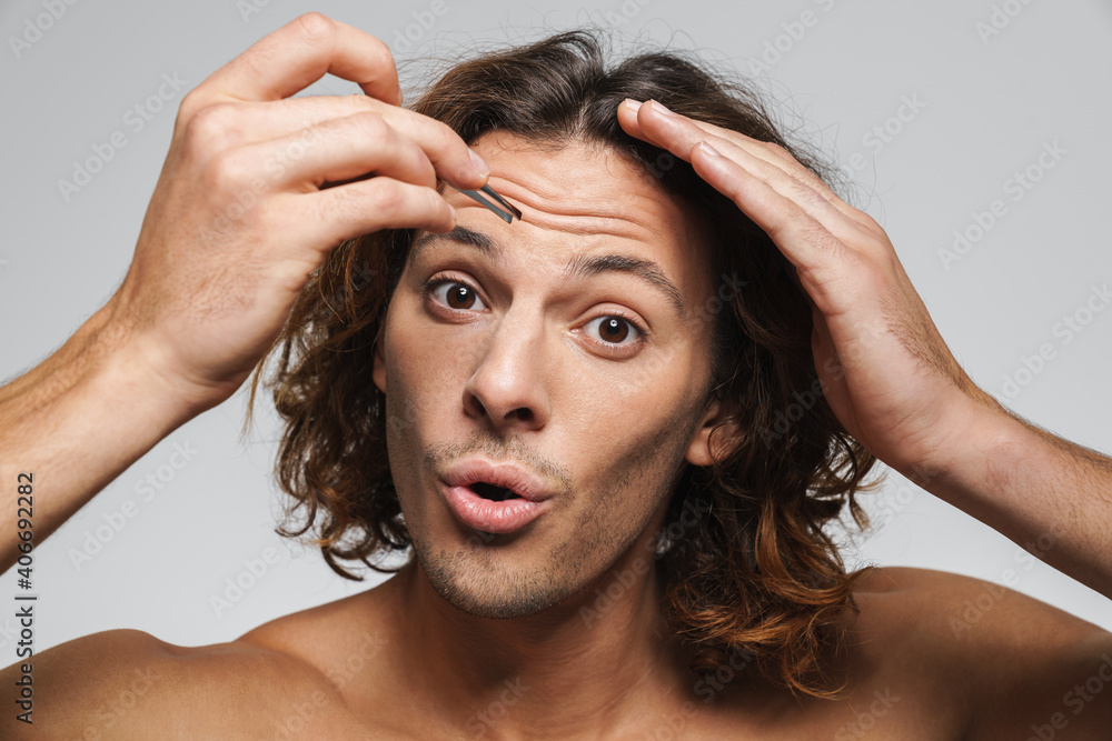 Surprised shirtless handsome guy plucking eyebrows with tweezers Stock ...