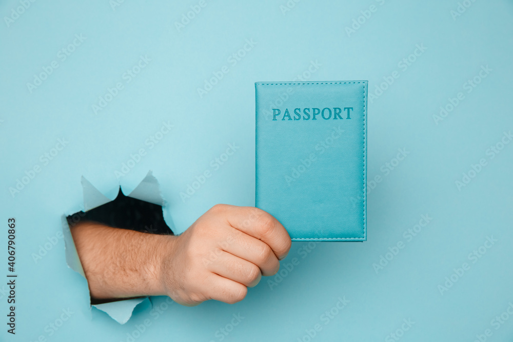 Traveler tourist man hand hold passport from a torn hole in blue paper ...