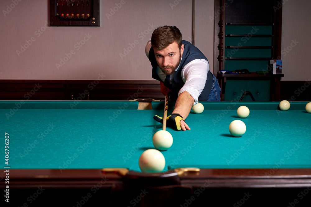 man is playing snooker, young male is aiming to shoot the snooker ball ...