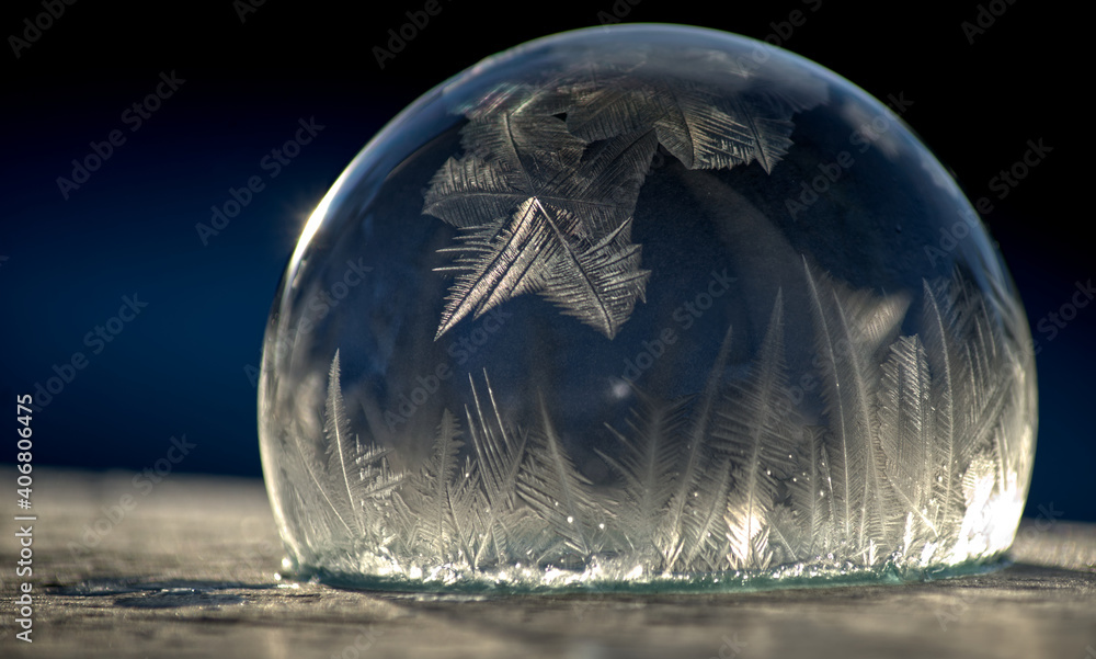 Soap bubble side lite by sun as ice crystals form in the wall structure ...