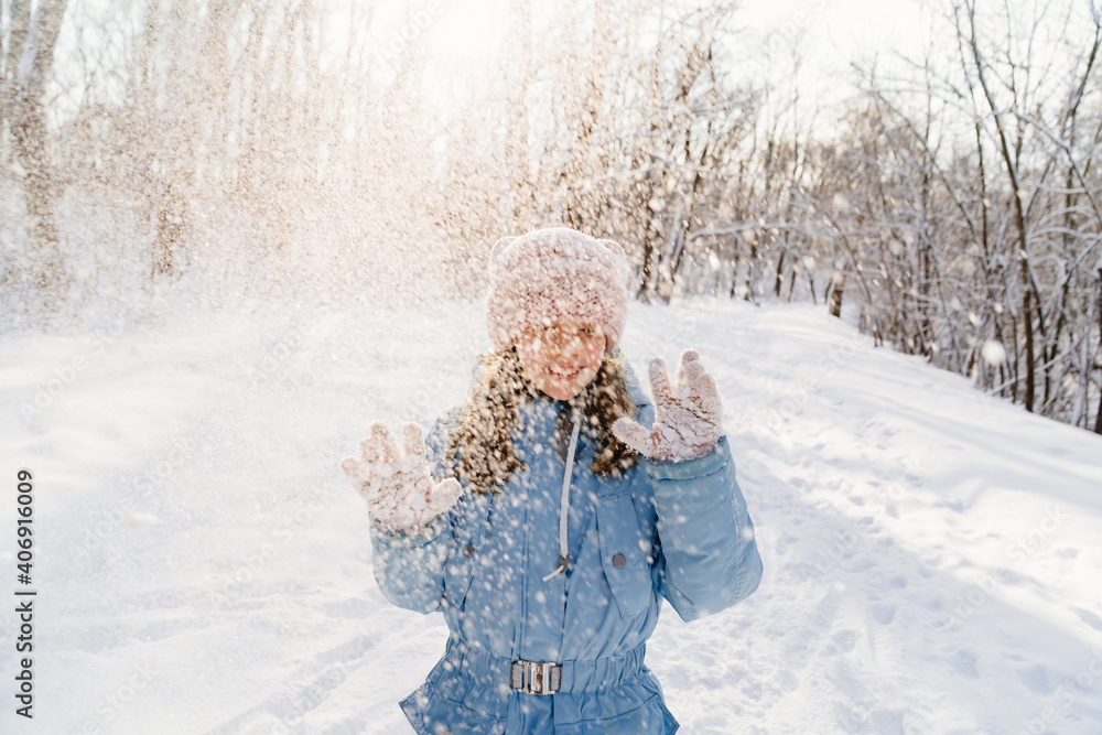 A teen girl in a blue coat shows gloves with stuck the snow while ...