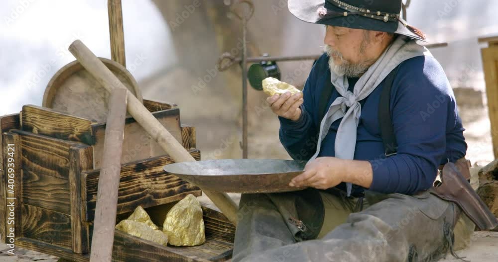 Gold digger wearing on cowboy hat and cowboy boots sitting using gold ...
