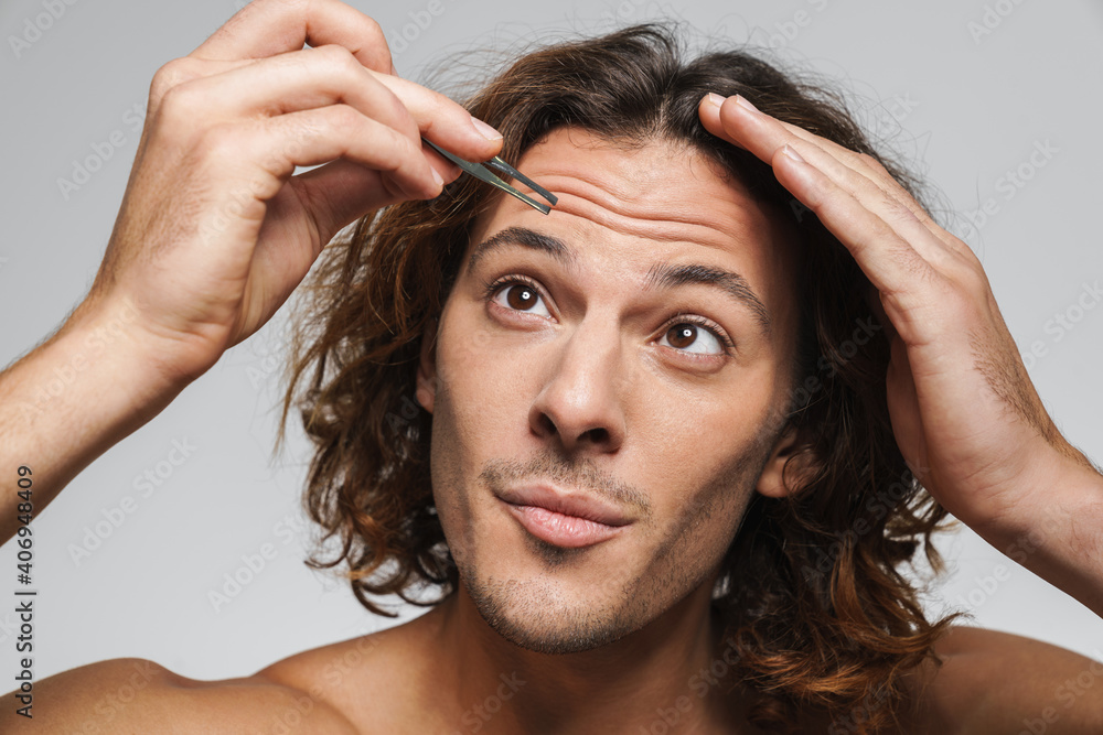 Focused shirtless handsome guy plucking eyebrows with tweezers Stock ...