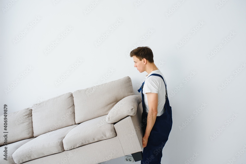 Loader moves sofa, couch. worker in overalls lifts up sofa, white ...