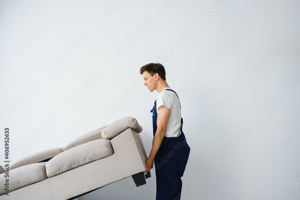 Loader moves sofa, couch. worker in overalls lifts up sofa, white ...
