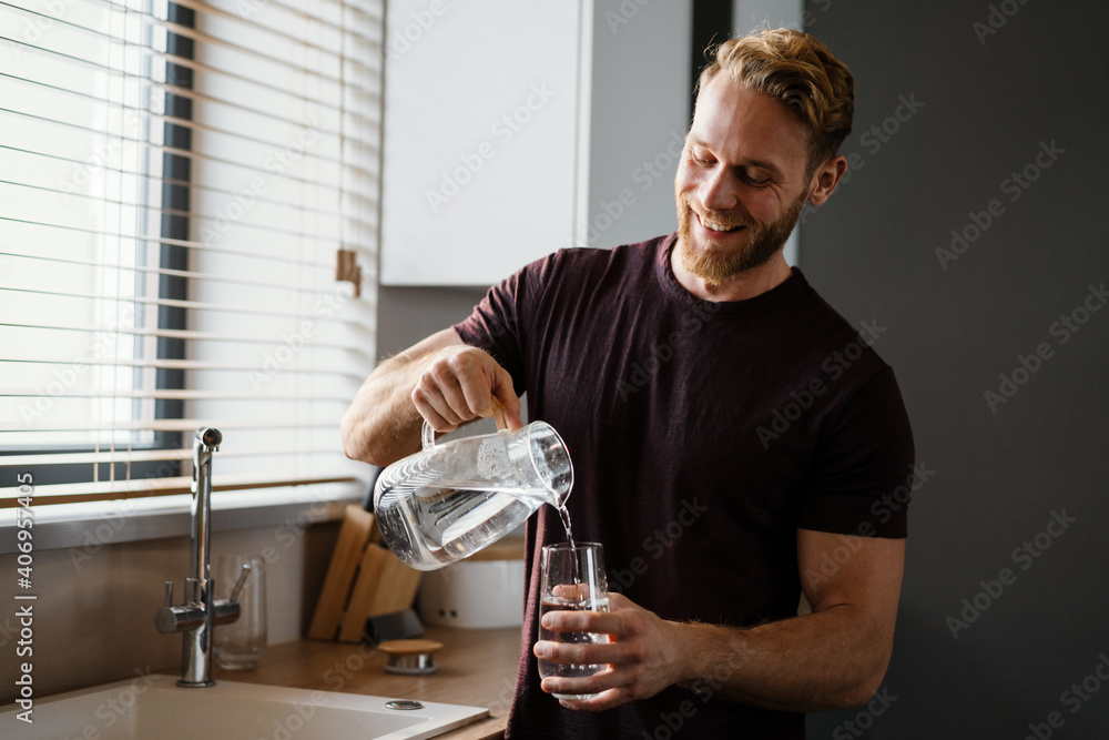 Attractive young man pouring water from a juf in a glass Stock Photo ...