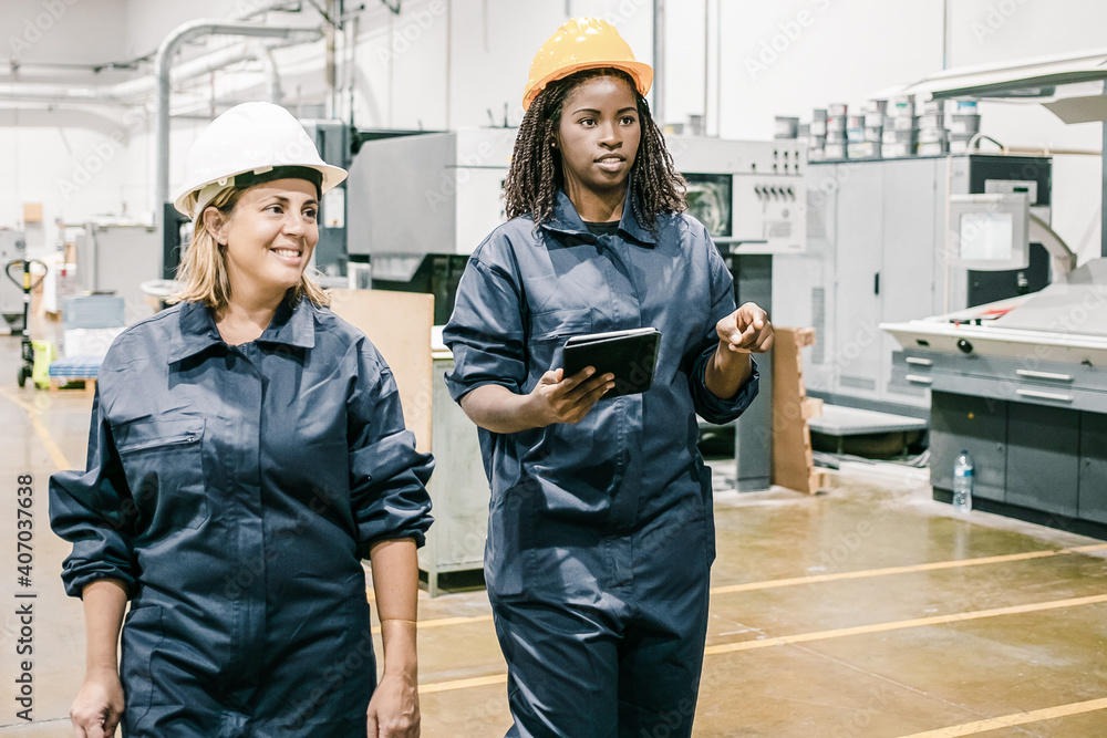 African American worker pointing, talking with colleague and holding ...