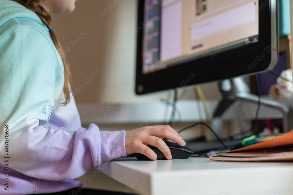 Child using a computer at home to do school work in a bedroom during ...
