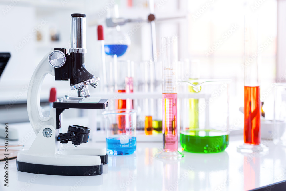 Microscope and test tubes with lab glassware in laboratory background ...
