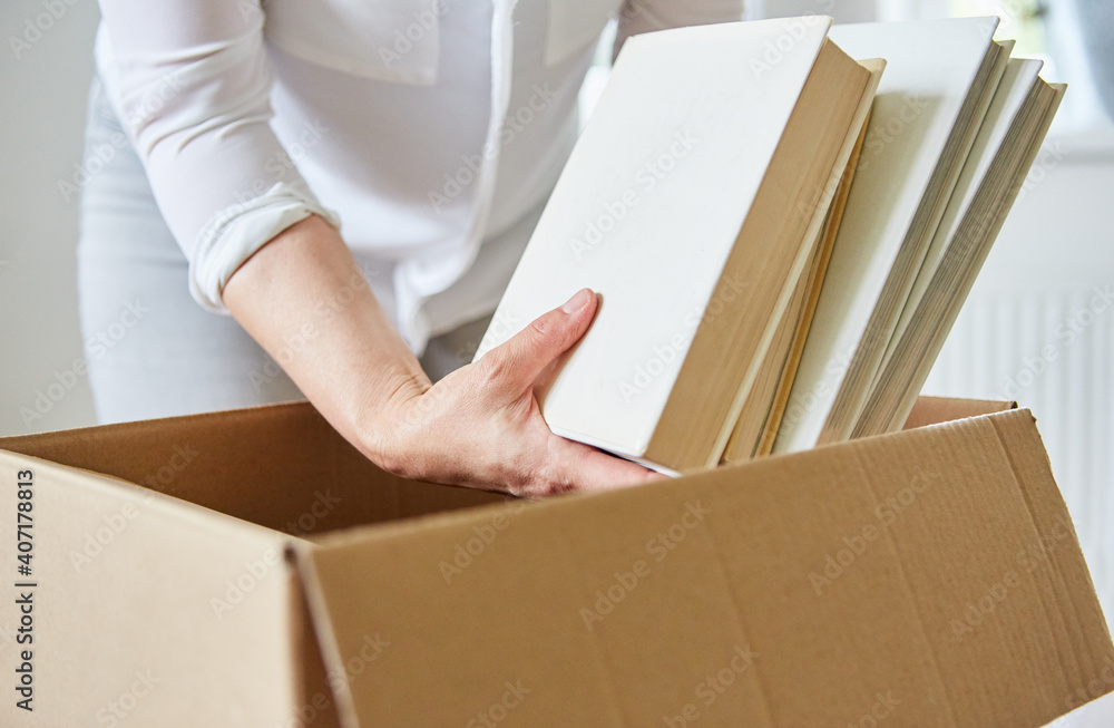 Woman unpacks books from a moving box Stock Photo | Adobe Stock