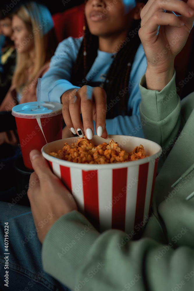 Foto de Close up of red with white basket of popcorn. Young couple are ...