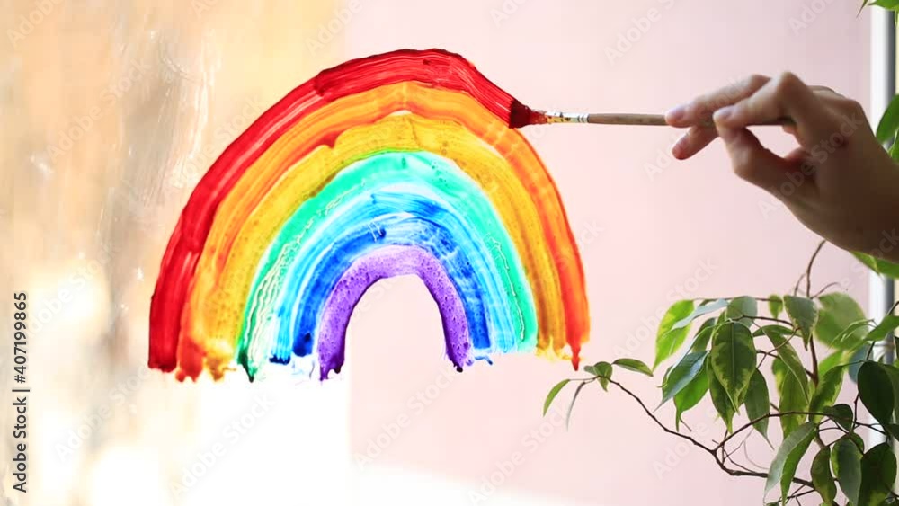 Little girl painting rainbow on window during Covid-19 quarantine at ...