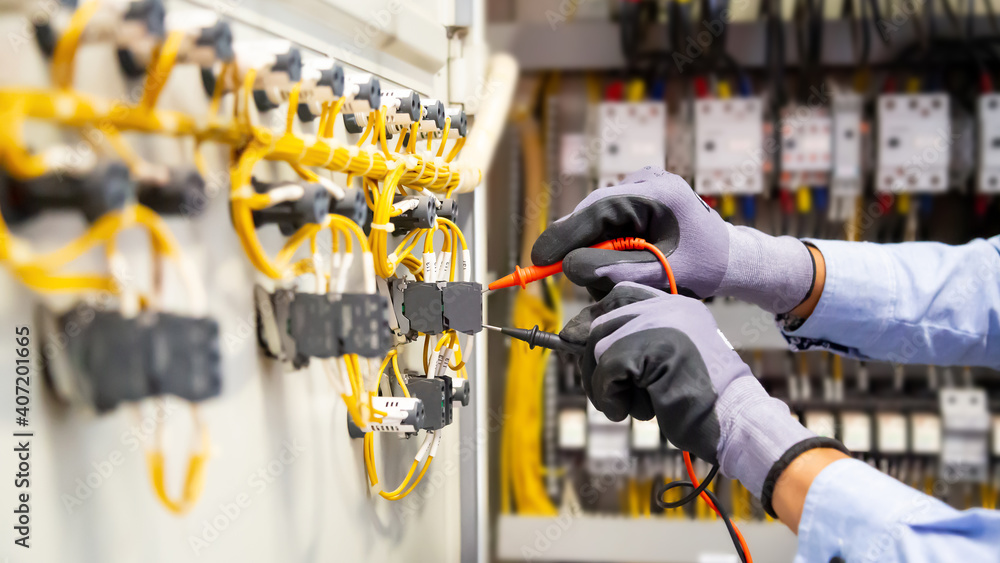 Electrical engineer using digital multi-meter measuring equipment to ...