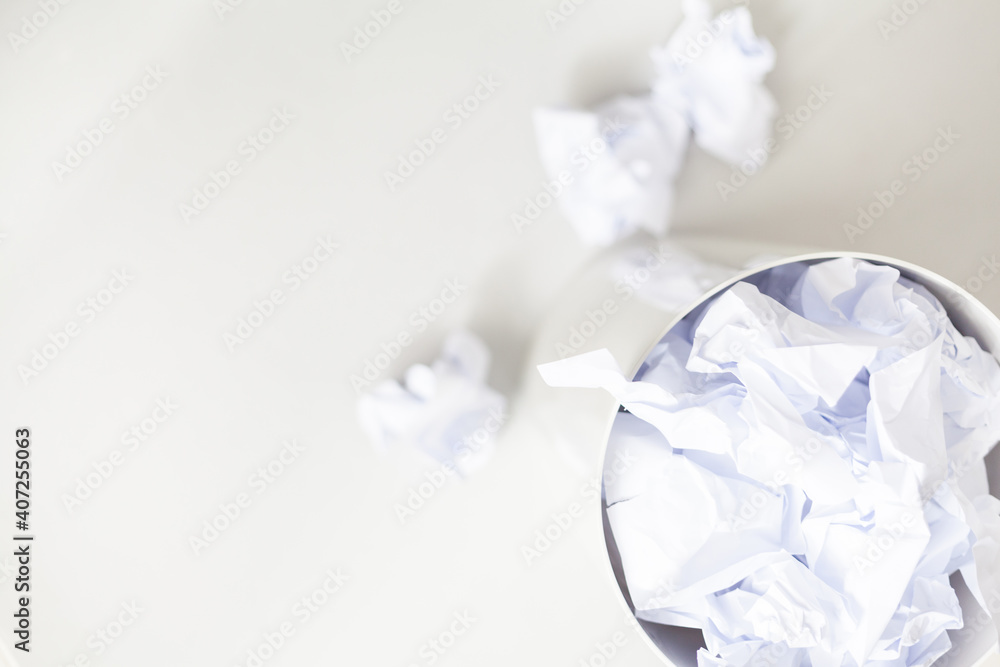 Overfilled white recycle bin on a light background with crumpled ...