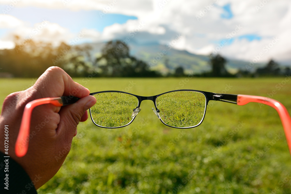 hand holding lenses showing a person's focus and myopia, seeing nature ...