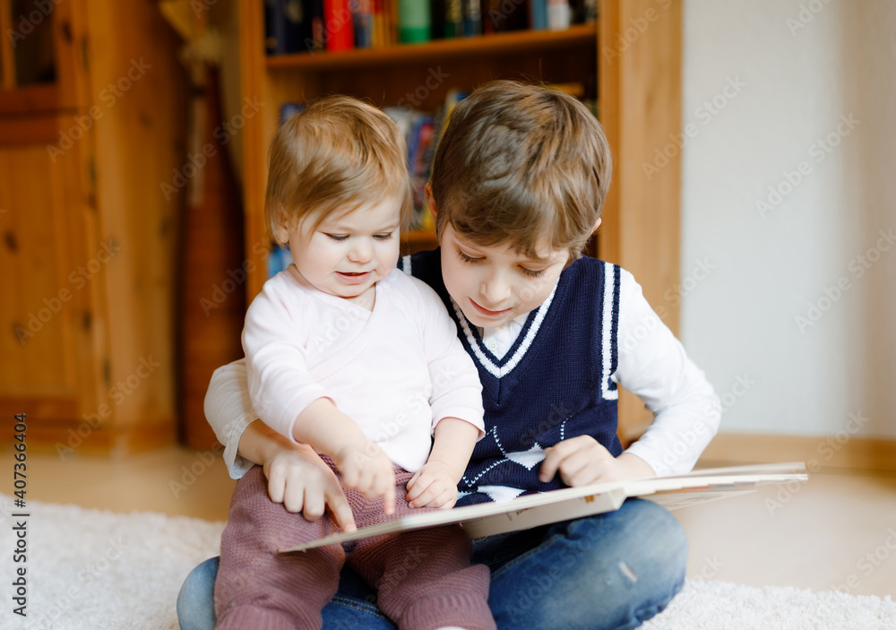 School kid boy reading book for little toddler baby girl, Two siblings ...
