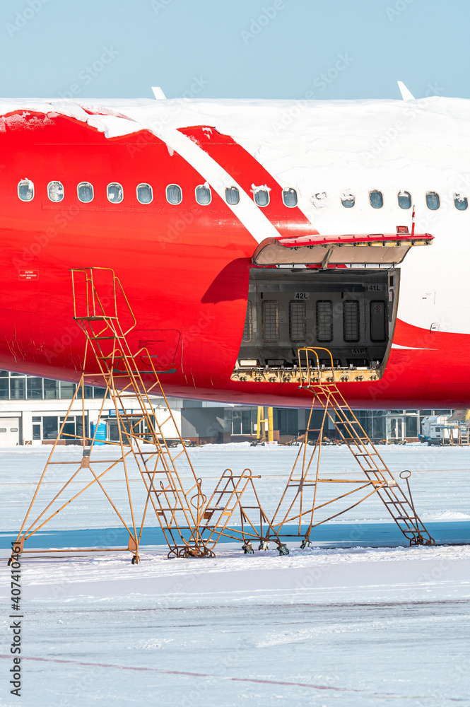 Winter scene of the airport. Modern twin-engine cargo airplane stand at ...