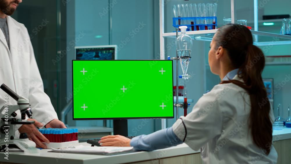 Scientist analysing blood sample and typing at computer with green ...