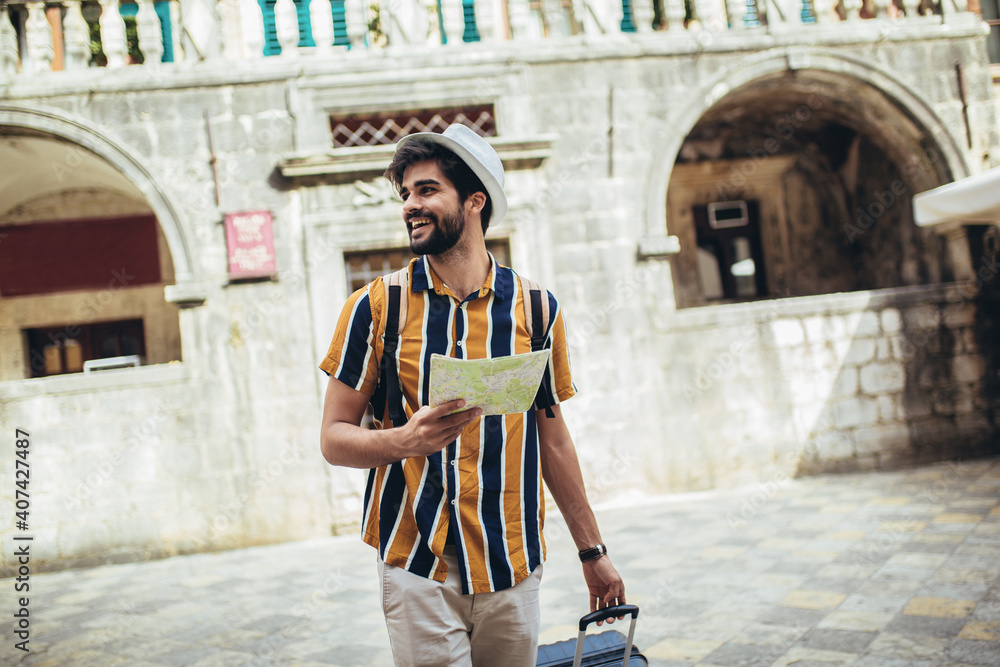 Happy tourist with backpack is making travel across city uses a map for ...