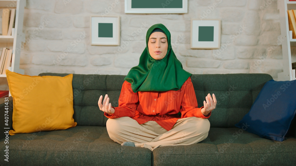 Muslim woman wearing a hijab is practicing yoga at home. Meditation ...