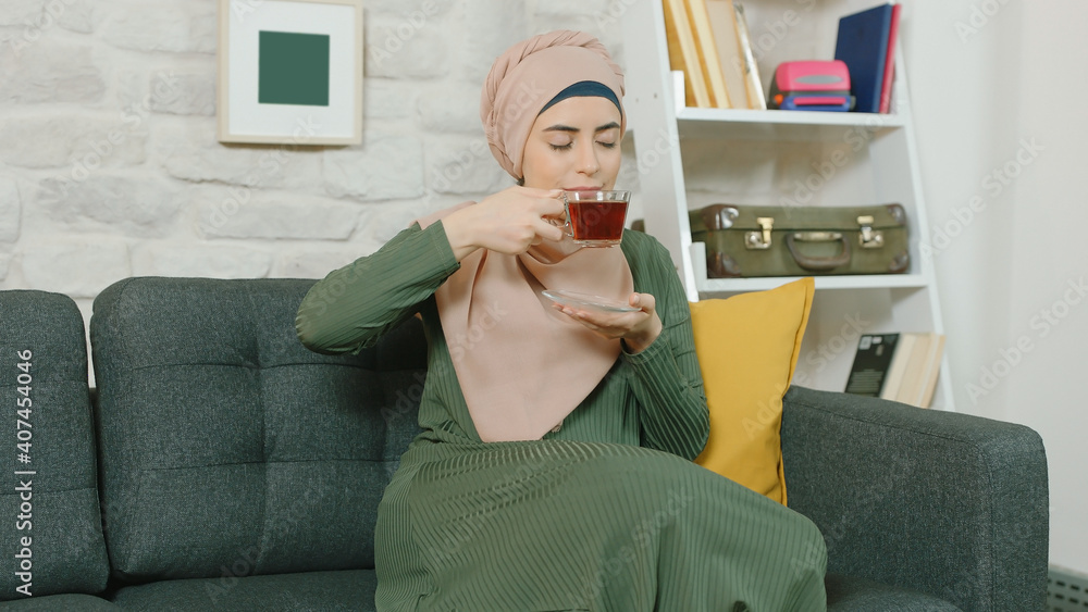 Muslim woman wearing a hijab is drinking tea at her home. Stock Photo ...