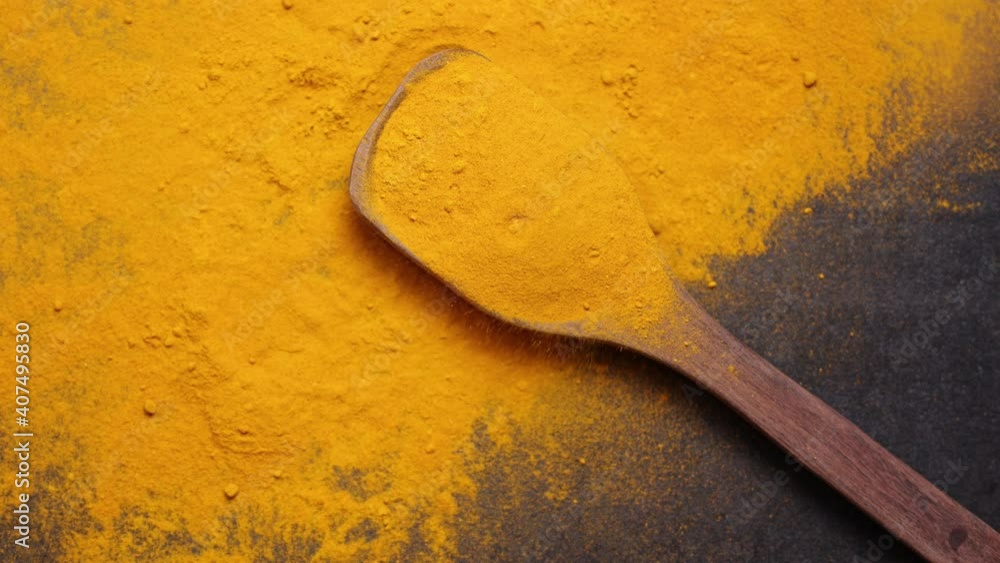 Indian spices turmeric powder in wooden spoon falling on black ...