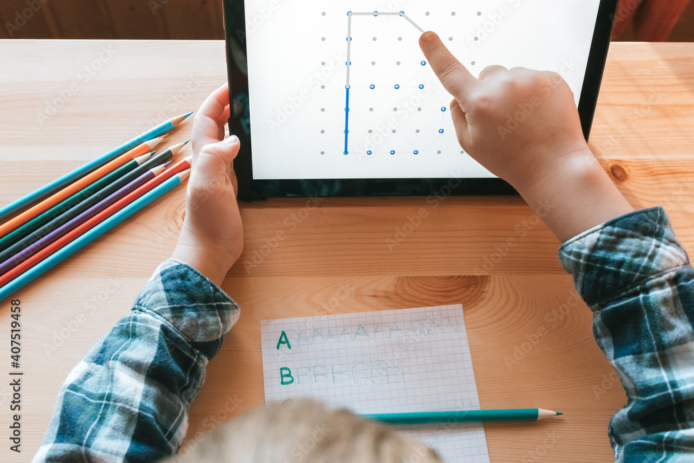 Cute child uses app on tablet to study and draw at home, distance ...