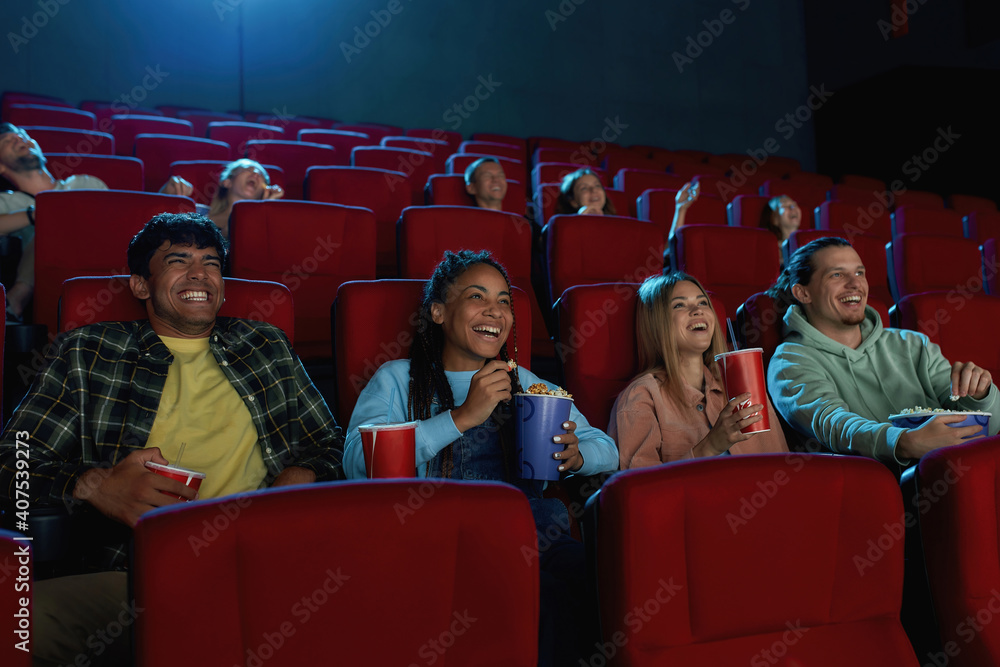 A group of happy diverse friends laughing while watching movie together ...