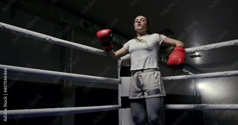 Angry female boxer resting in ring corner. Long angle of aggressive ...