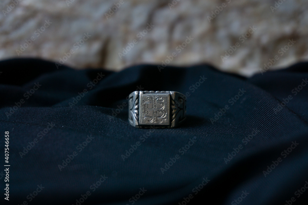 Silver ring with a dark fabric background, the ring has a background ...