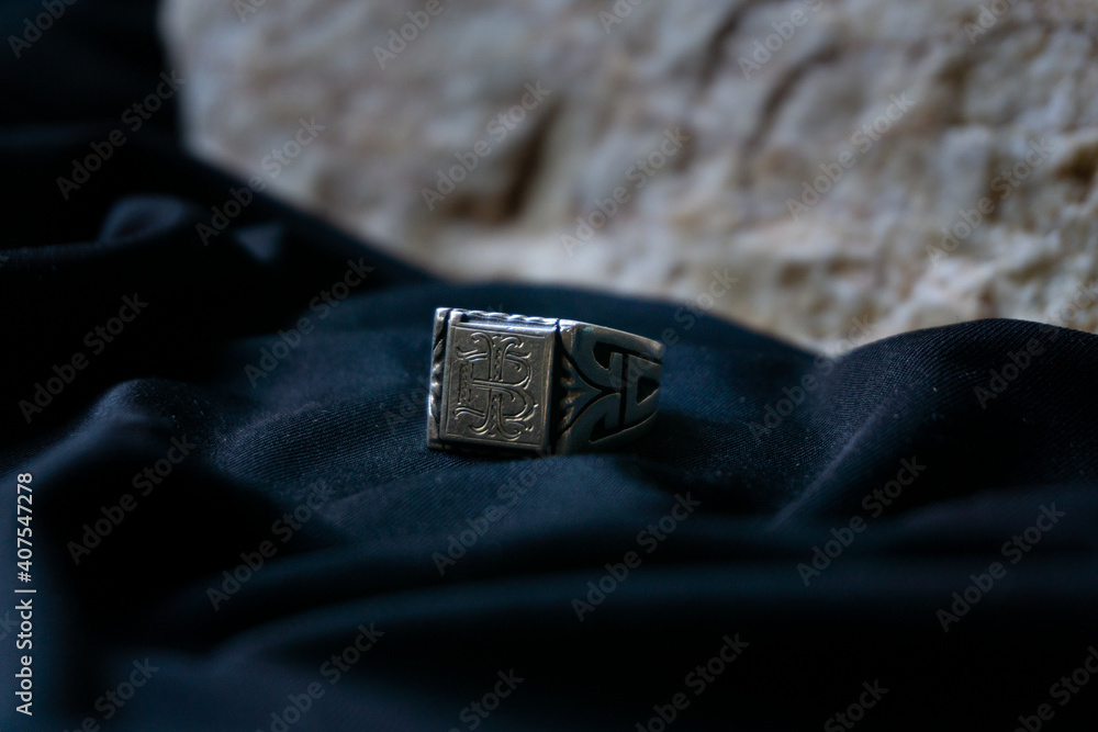 Silver ring with a dark fabric background, the ring has a background ...