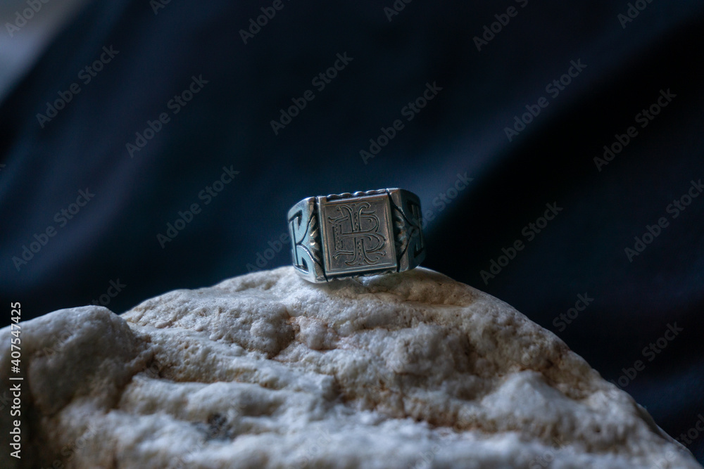 Silver ring with a dark fabric background, the ring has a background ...
