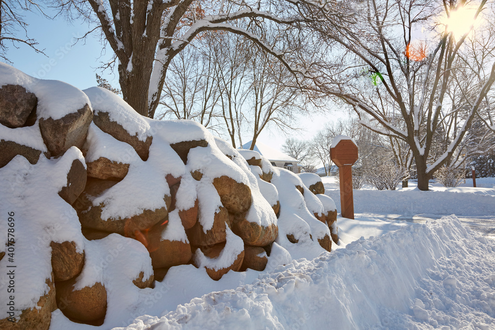 Way too much snow on my street with a big rock wall and fancy stop sign ...
