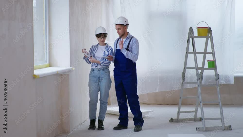 professional male and female builders in safety helmets choose new wall ...
