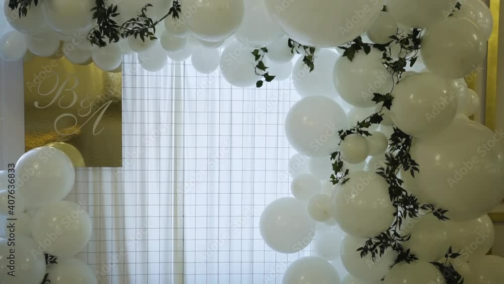 Exquisite wedding arch made of white balloons and branches of a green ...