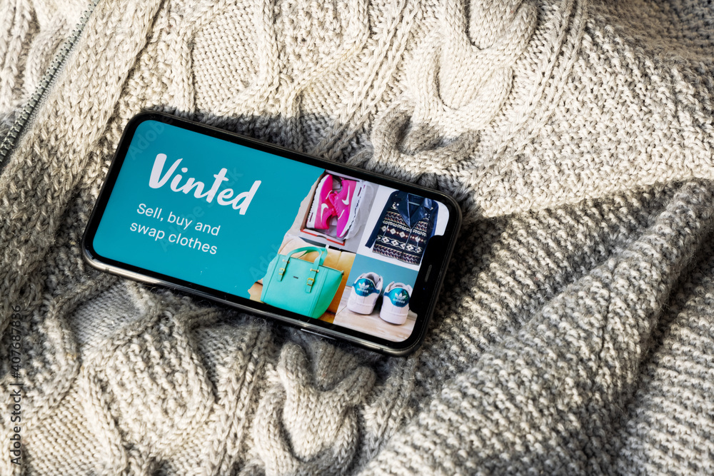 Iphone with Vinted logo on screen on vintage knitted fabric. Vinted is ...