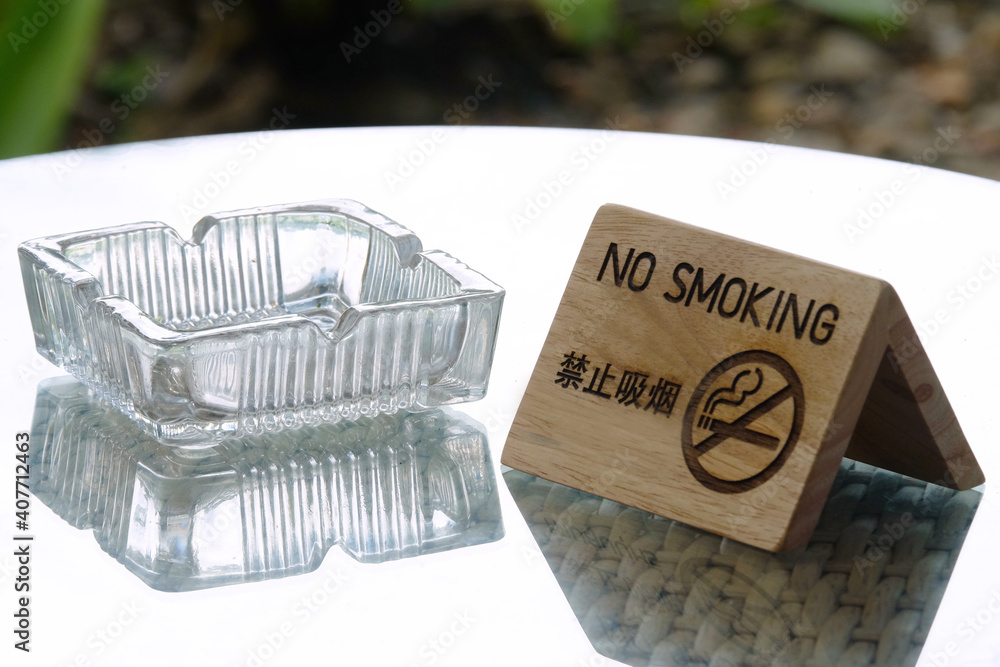 No smoking sign written in English and Chinese on wood panel with ash ...