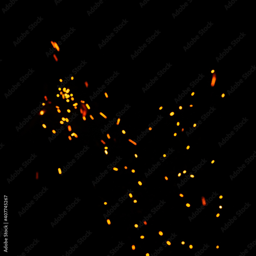 Particles of burning embers fly and glow isolated in the night sky ...