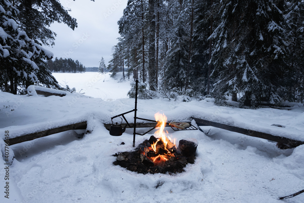 Bright bonfire in a winter forest. Beautiful snow covered trees. Kettle ...